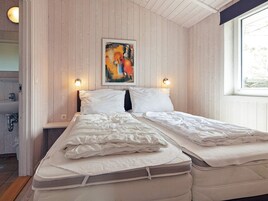 Quarto com duas camas, paredes de madeira, um quadro e uma janela.