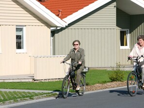 Duas pessoas andando de bicicleta em uma rua residencial.