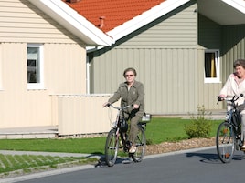Duas pessoas andando de bicicleta em uma rua residencial.