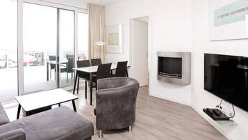 Uma sala de estar moderna com televisão de tela plana, lareira e área de jantar com mesa e cadeiras.