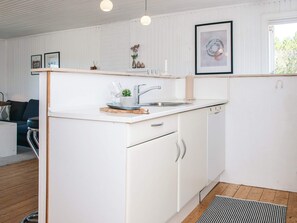 Cozinha moderna com armários brancos, pia de aço inoxidável e iluminação pendente.