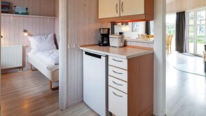 Quarto compacto com cama, cozinha compacta e vista pela janela.