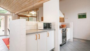 Cozinha moderna com armários brancos, micro-ondas e forno.