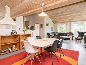 Um interior moderno com área de refeições, sofás e cozinha.