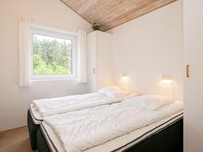 Quarto com cama, janela com cortinas e duas luminárias na parede.