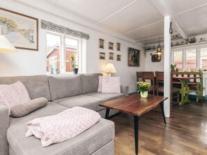 Uma sala de estar com sofá, mesa de centro de madeira e área de jantar com mesa e cadeiras.