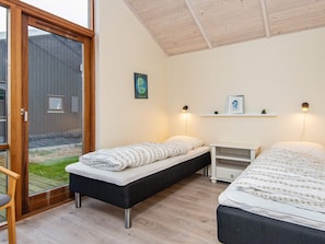 Quarto com duas camas, teto de madeira e vista através de uma porta de vidro.