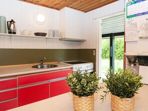 Cozinha com pia, fogão e armários vermelhos. Há duas cestas trançadas com plantas sobre o balcão.