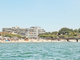 Hotel à beira-mar com vários andares, praia em primeiro plano e céu claro.