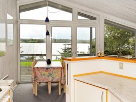 Cozinha com vista para um lago, mesa de jantar com cadeiras e luminária pendente.