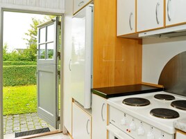 Uma cozinha com fogão, armários e uma porta que dá para um jardim.