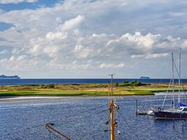Uma marina com barcos, um cais e um navio ao longe no horizonte.