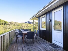 Um terraço com mobiliário de exterior, uma porta e vista para uma colina.