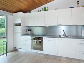 Cozinha moderna com armários brancos, bancada de aço inoxidável e lava-louças.