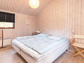 Quarto com cama, janela, cadeira e uma pequena mesa.