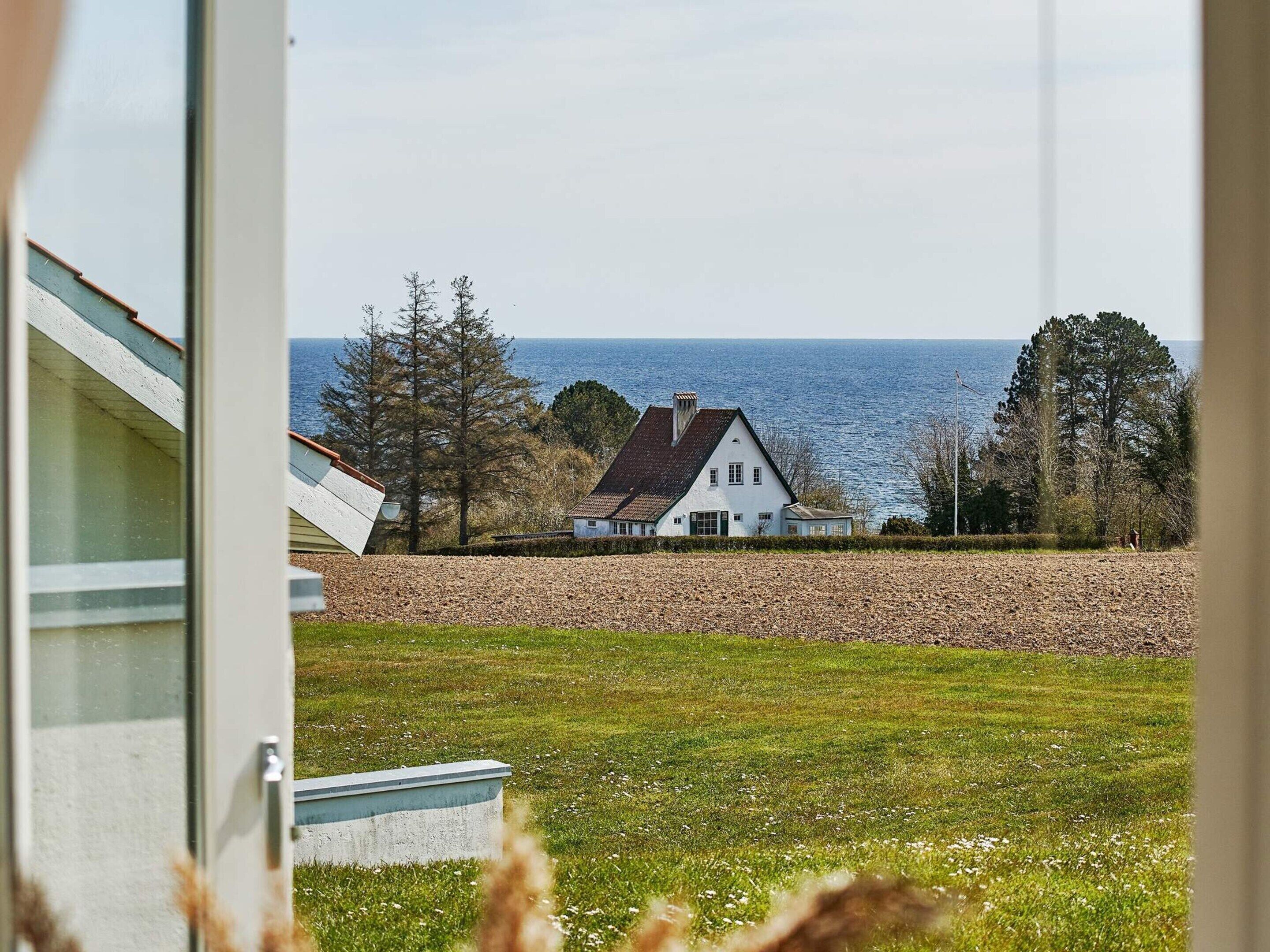 Uma casa à beira-mar com vista para o mar, uma parede de pedra e um campo gramado.