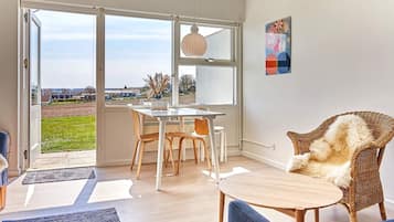 Um interior moderno com área de jantar, uma cadeira de vime e vista através de amplas janelas.