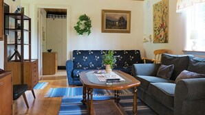 Uma sala de estar com teto de madeira, um sofá, uma mesa de centro e uma estante.