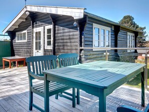 Uma cabana de madeira com varanda, uma mesa e cadeiras.