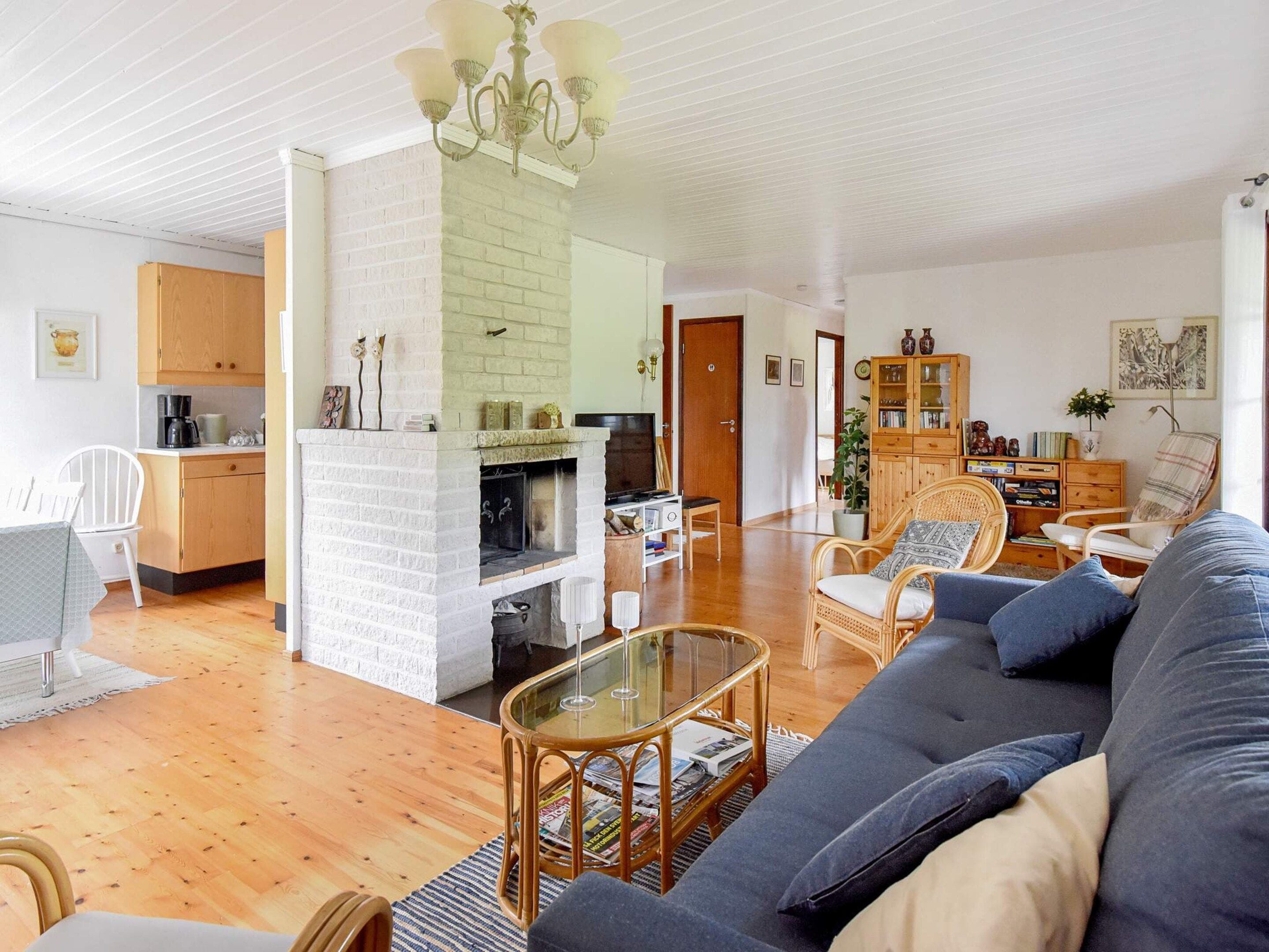 Uma sala de estar com lareira, um sofá, uma mesa de centro e um espaço de jantar com armários de madeira.