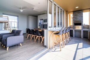 Uma cozinha moderna com lareira de pedra, área de jantar com banquetas e sala de estar com sofás.