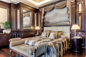 Um quarto luxuoso com uma cama grande, um sofá e uma pintura de uma paisagem na parede.