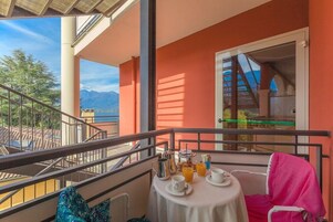 Varanda com mesa posta para o café da manhã, uma cadeira e vista para montanhas.