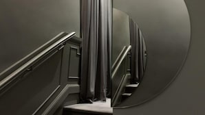 Uma escadaria moderna com design elegante, incluindo corrimão e um detalhe circular na parede.