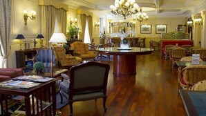 Um hall de hotel espaçoso com um lustre imponente, áreas de estar confortáveis e uma mesa de centro.
