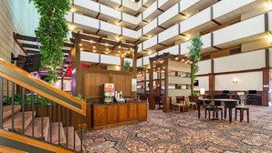 Um hall amplo com uma recepção central, áreas de estar e um tapete estampado.