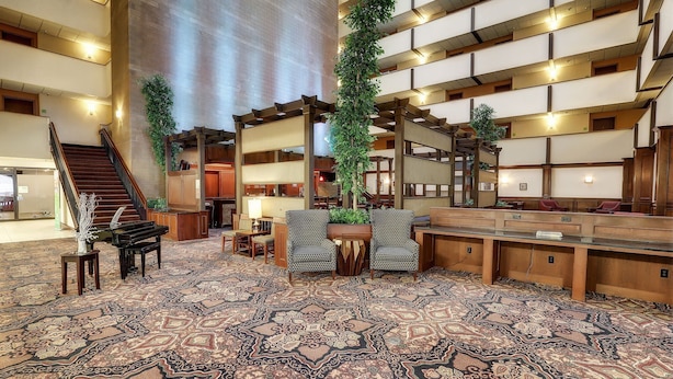 Um lobby amplo com um piano de cauda, área de estar e escadaria.