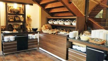 Uma cozinha com armários de madeira, piso ladrilhado e diversos alimentos sobre o balcão.