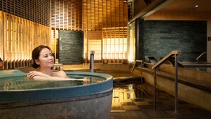 Uma área de spa com uma banheira de hidromassagem grande, ripas de madeira e piso xadrez.