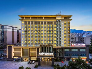 Um hotel grande com vários andares, entrada destacada e uma bandeira na frente.