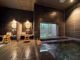 Um spa moderno com hidromassagem, banquinhos de madeira e uma grande janela com vista para o verde.