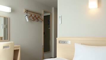 Quarto de hotel com cama, mesa de cabeceira, espelho, luz acoplada à parede e porta que dá para outro quarto.