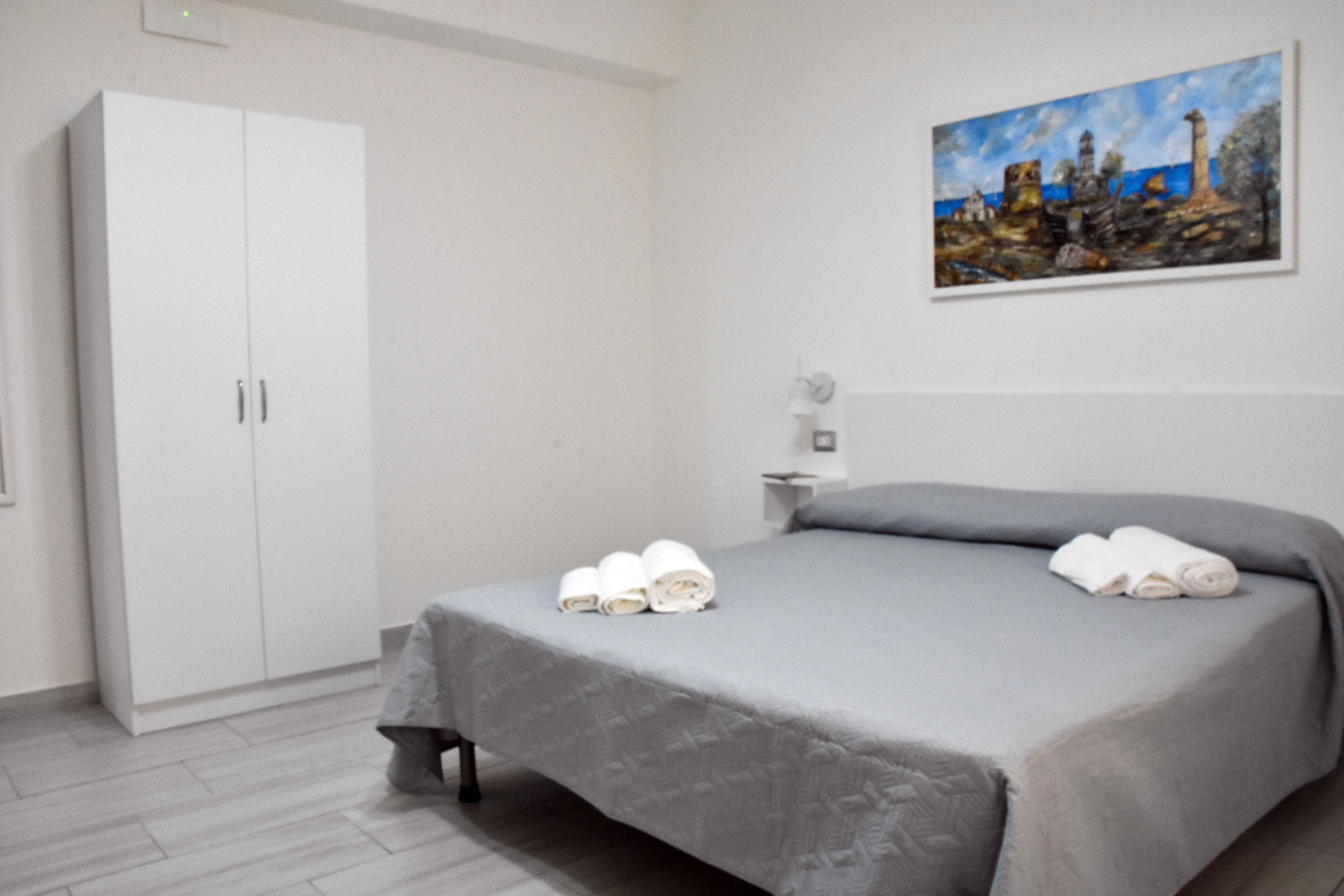 Quarto com cama, guarda-roupa e um quadro na parede.