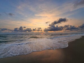 Uma praia com ondas e um pôr do sol.
