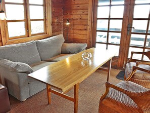 Interior em madeira com sofá, mesa e cadeiras de vime.