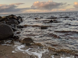 Uma costa rochosa com ondas quebrando nas pedras.