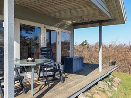 Uma área externa coberta com mesa e cadeiras, um armário azul e vista para a paisagem ao redor.
