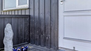 Fachada de madeira com porta branca e janela com tela.