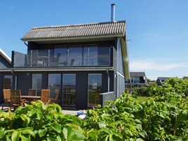 Uma casa moderna de dois andares, com varanda, janelas amplas e chaminé.