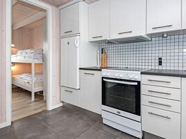 Cozinha compacta com fogão, forno e armários brancos.