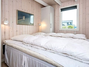 Quarto com cama, janela e um quadro fixado na parede.