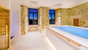 Um quarto de spa moderno com parede de pedra, uma banheira grande e uma porta de madeira.