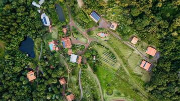 Vista aérea de uma área residencial com várias casas, painéis solares e um pequeno lago.