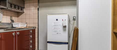 Uma cozinha compacta com armários vermelhos, uma geladeira branca e painel de azulejos.
