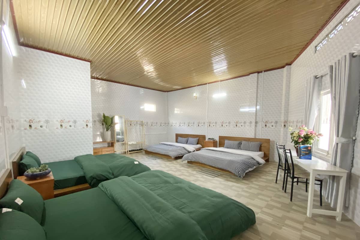 Um quarto espaçoso com duas camas, teto de madeira e uma grande janela com cortinas.