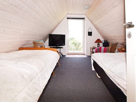 Quarto com duas camas, televisão e porta para uma varanda.